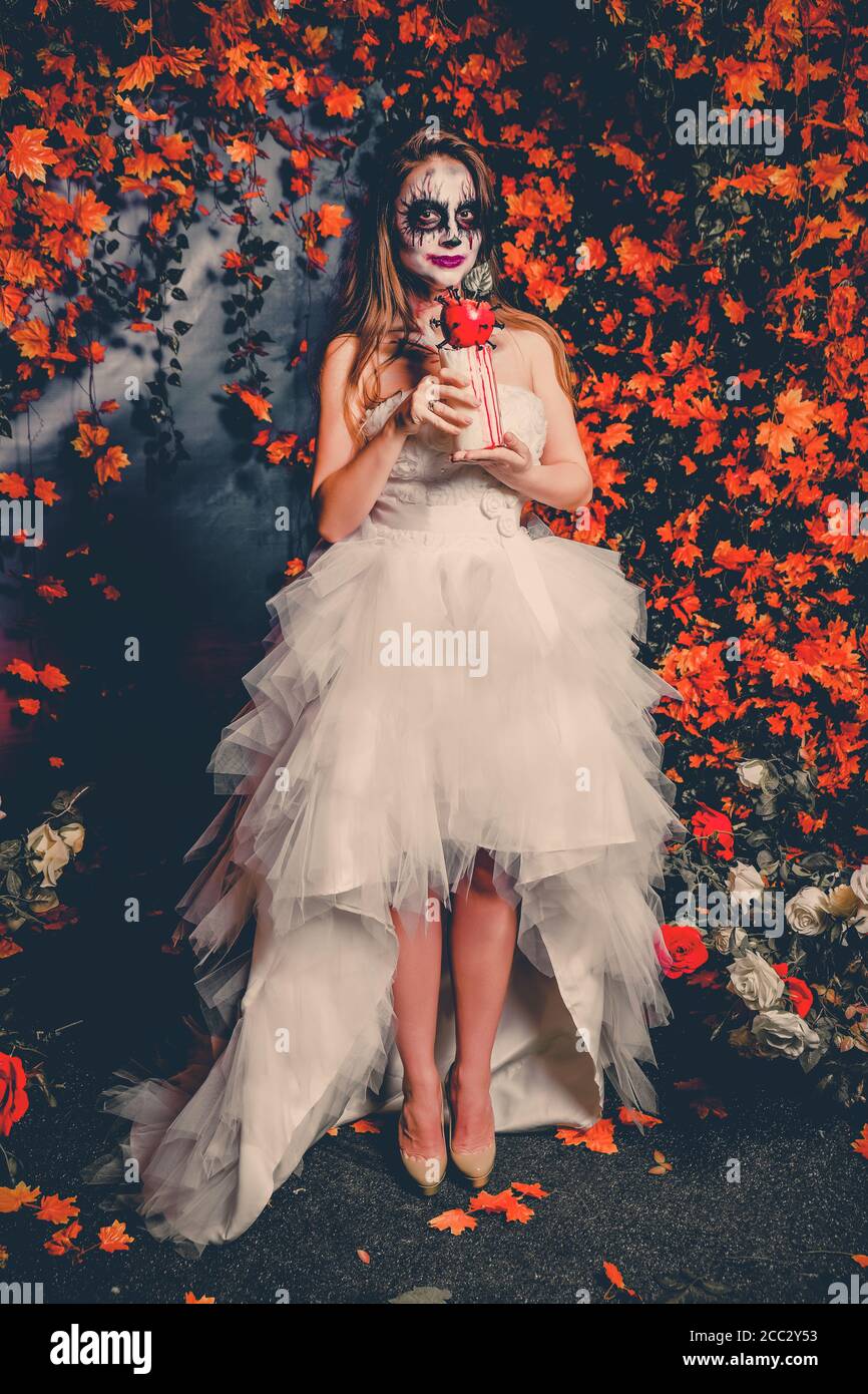 Girl in makeup for halloween and wedding dress holds bloody accessories ...