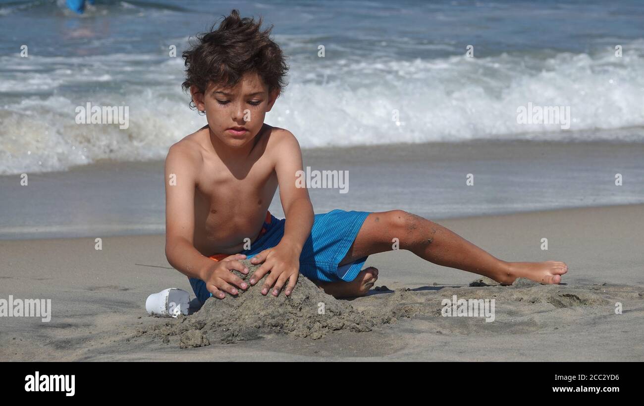 Young boy plays in the sand at the beach Stock Photo - Alamy