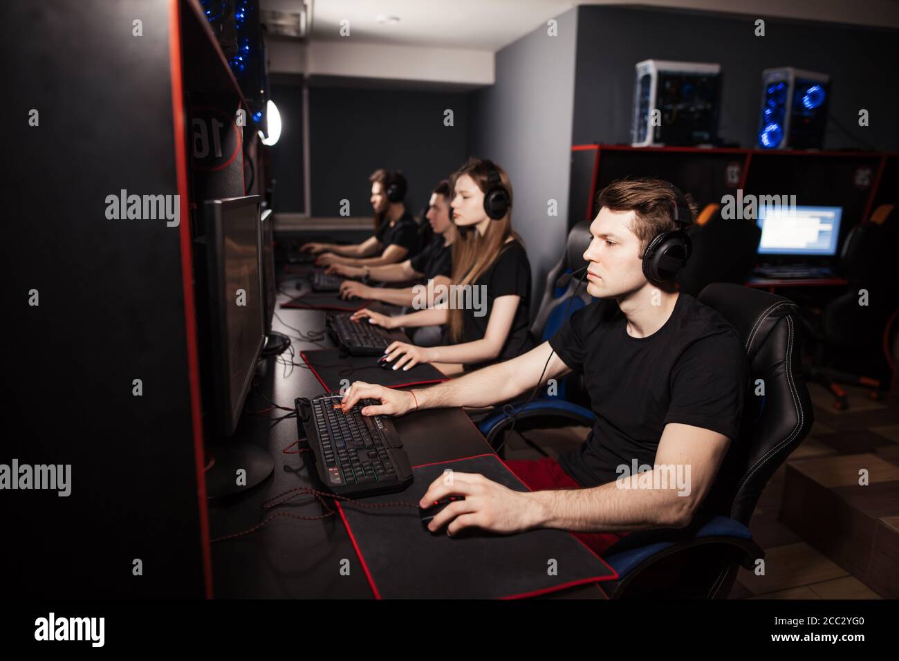 Group of adult male gamers sitting in a row behind the monitors, play ...