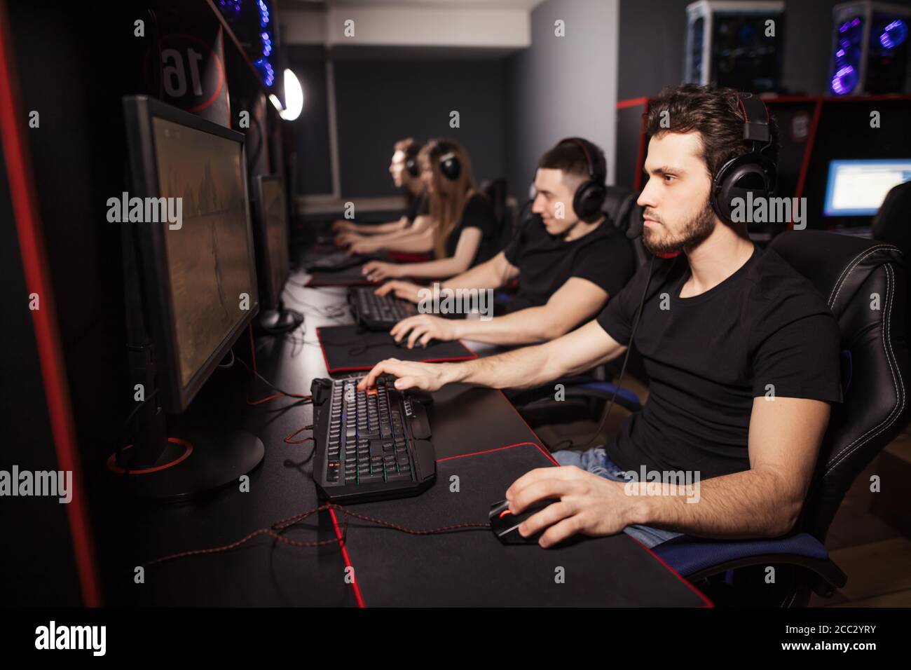 Group of adult male and female gamers sitting in a row behind the ...