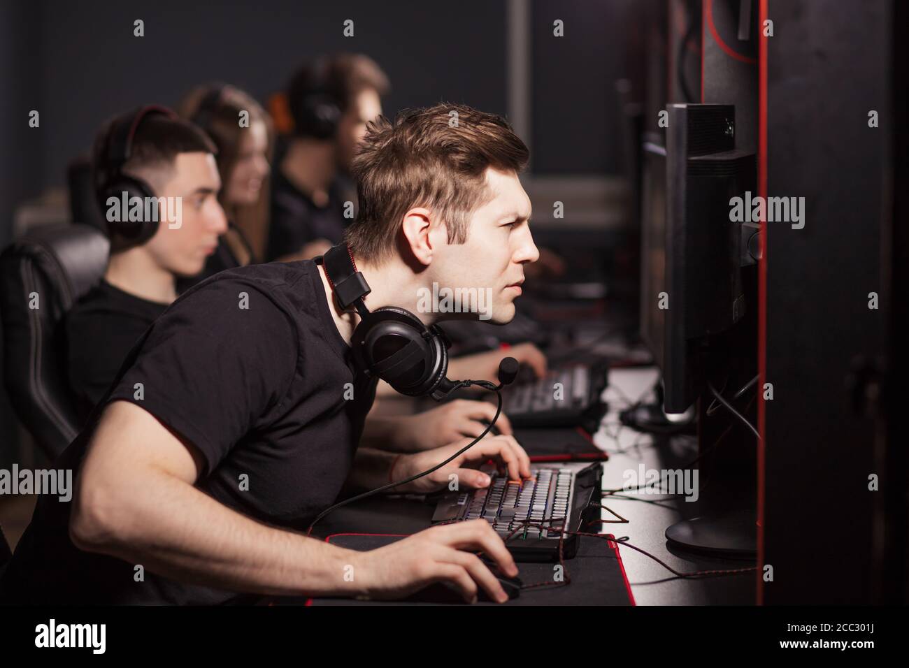 Group of adult male and female gamers sitting in a row behind the ...