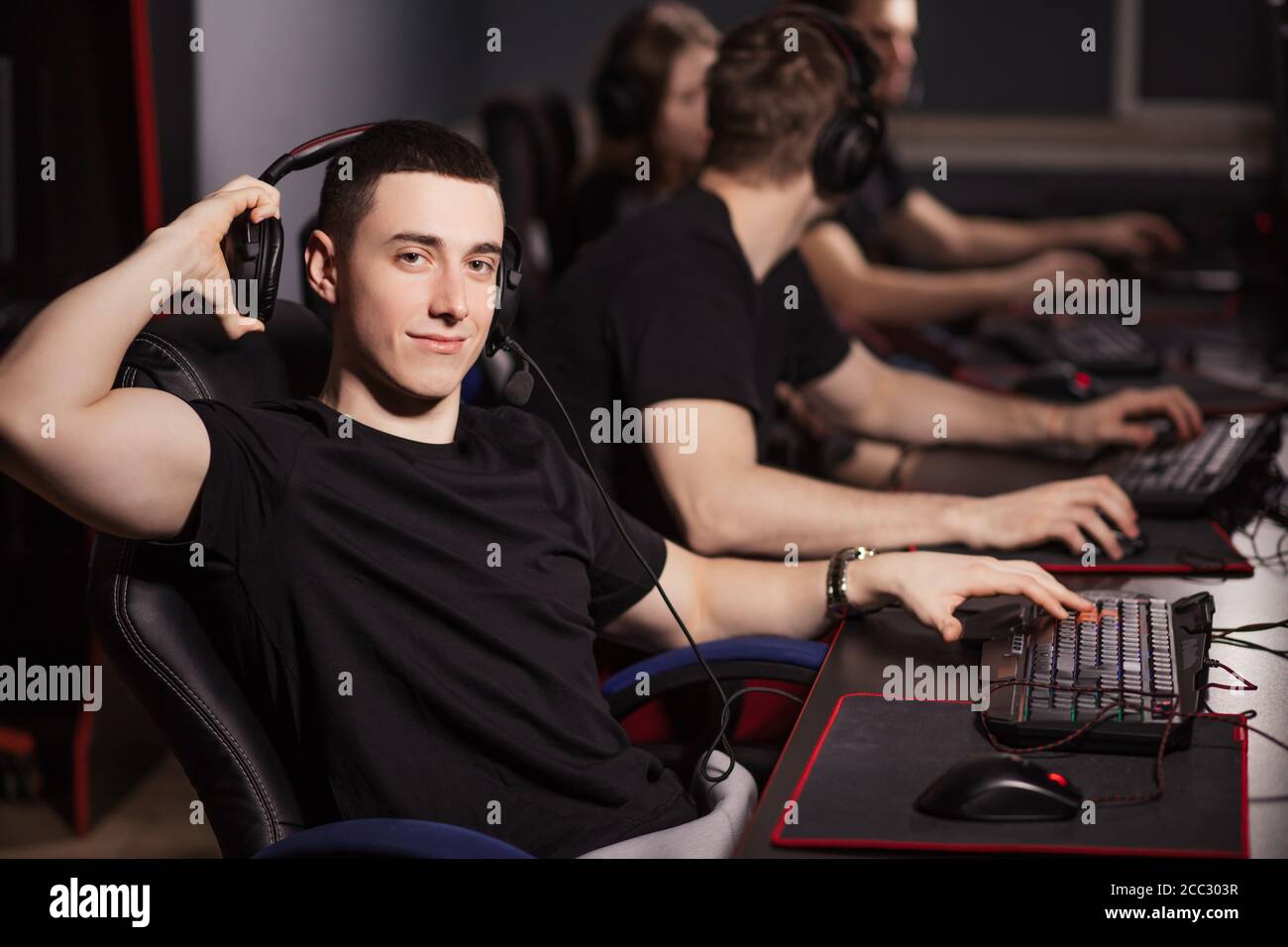 Satisfied smart gamer in black t-shirt sitting behind the computer ...