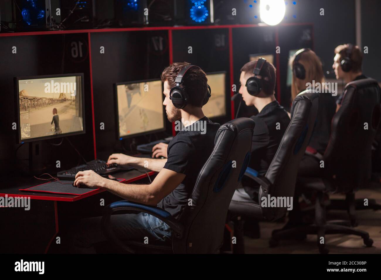 group of concentrated guys in headphones enjoying online video game on ...