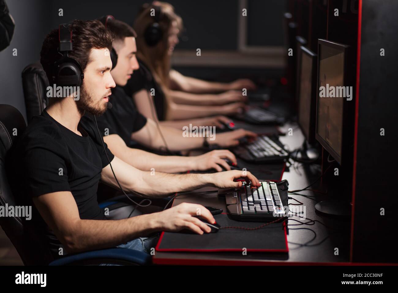 Group of adult male and female gamers sitting in a row behind the ...