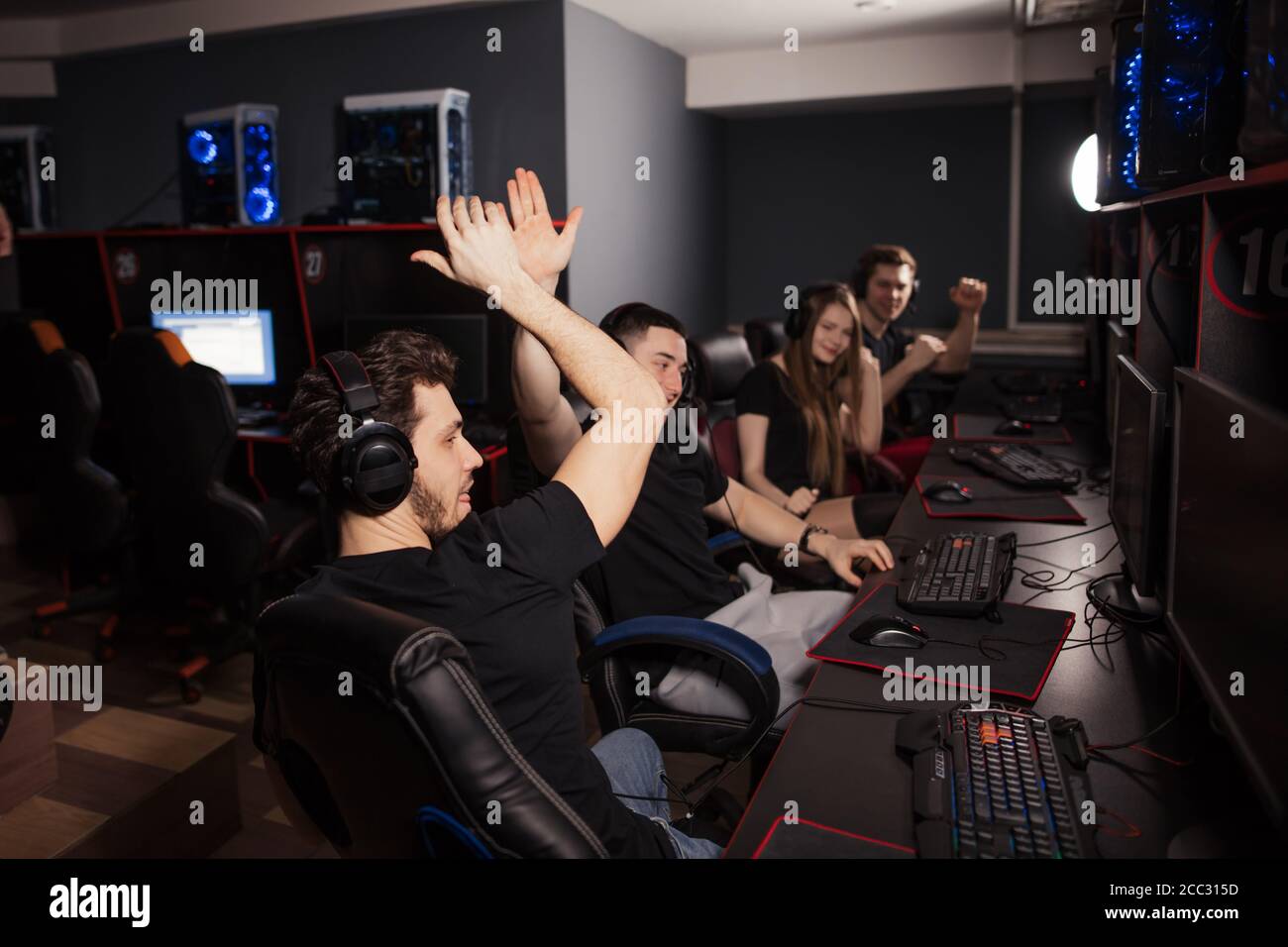 Enthusiastic e-sport gamers. Joyful young people sitting at powerful ...