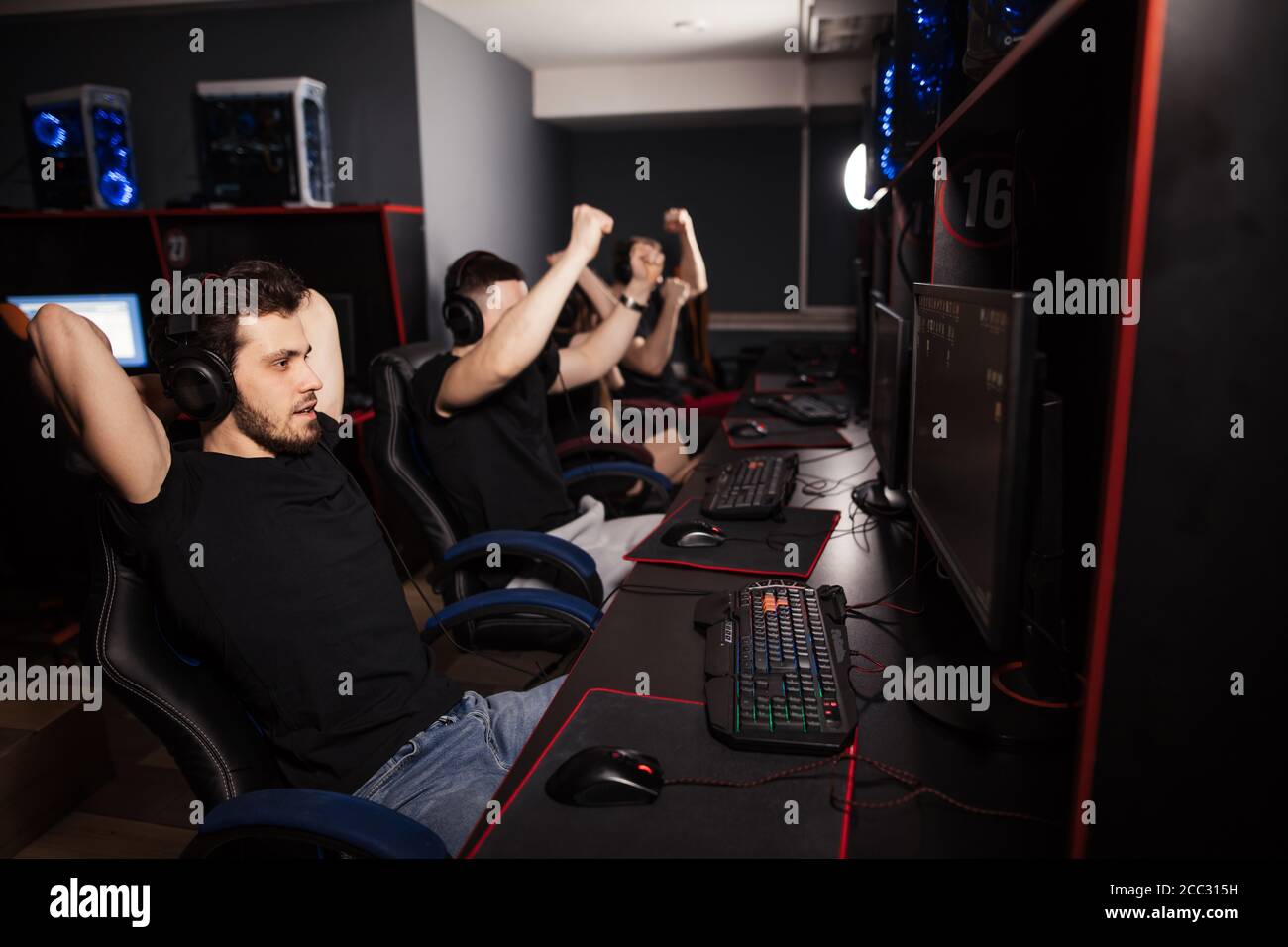 Enthusiastic e-sport gamers. Joyful young people sitting at powerful ...