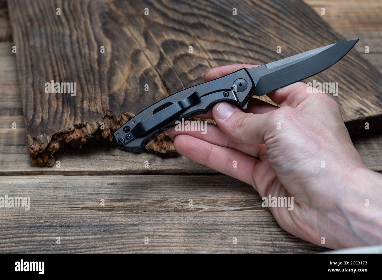 Small folding knife in hand. The blade and knife handle are black Stock ...