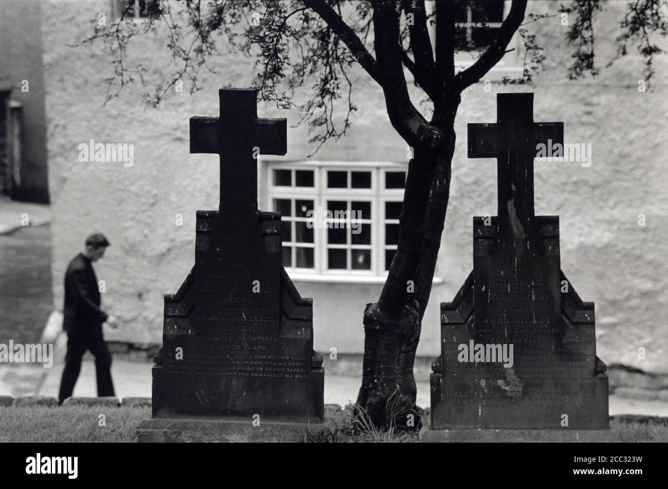 A man passes two war memorial grave crosses in Firbeck village, South ...