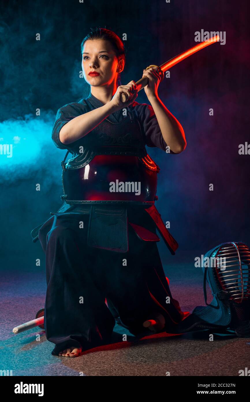 confident female kendo fighter isolated over smoky space. woman hold ...