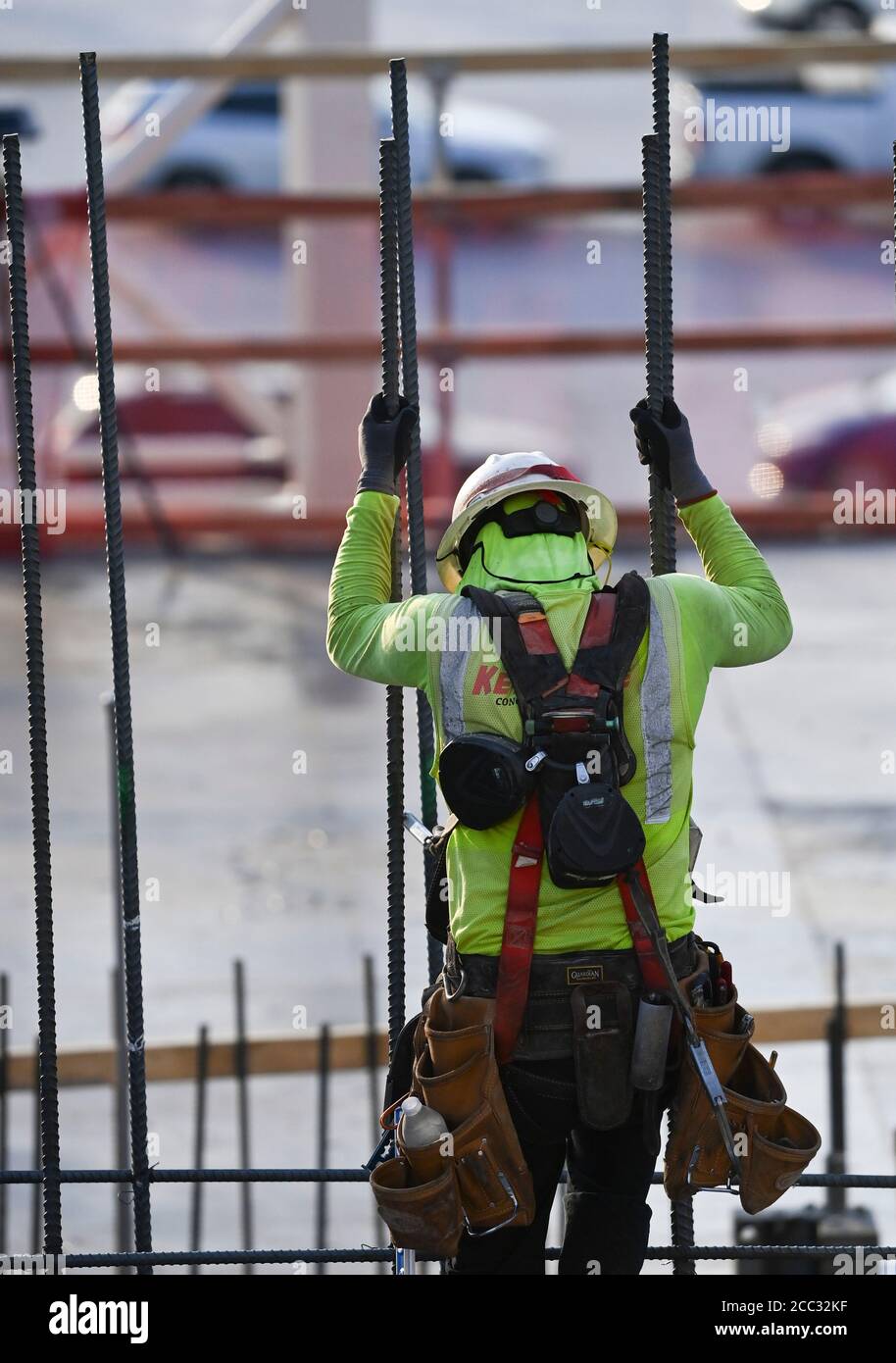Construction worker wearing safety gear and face covering on job site ...