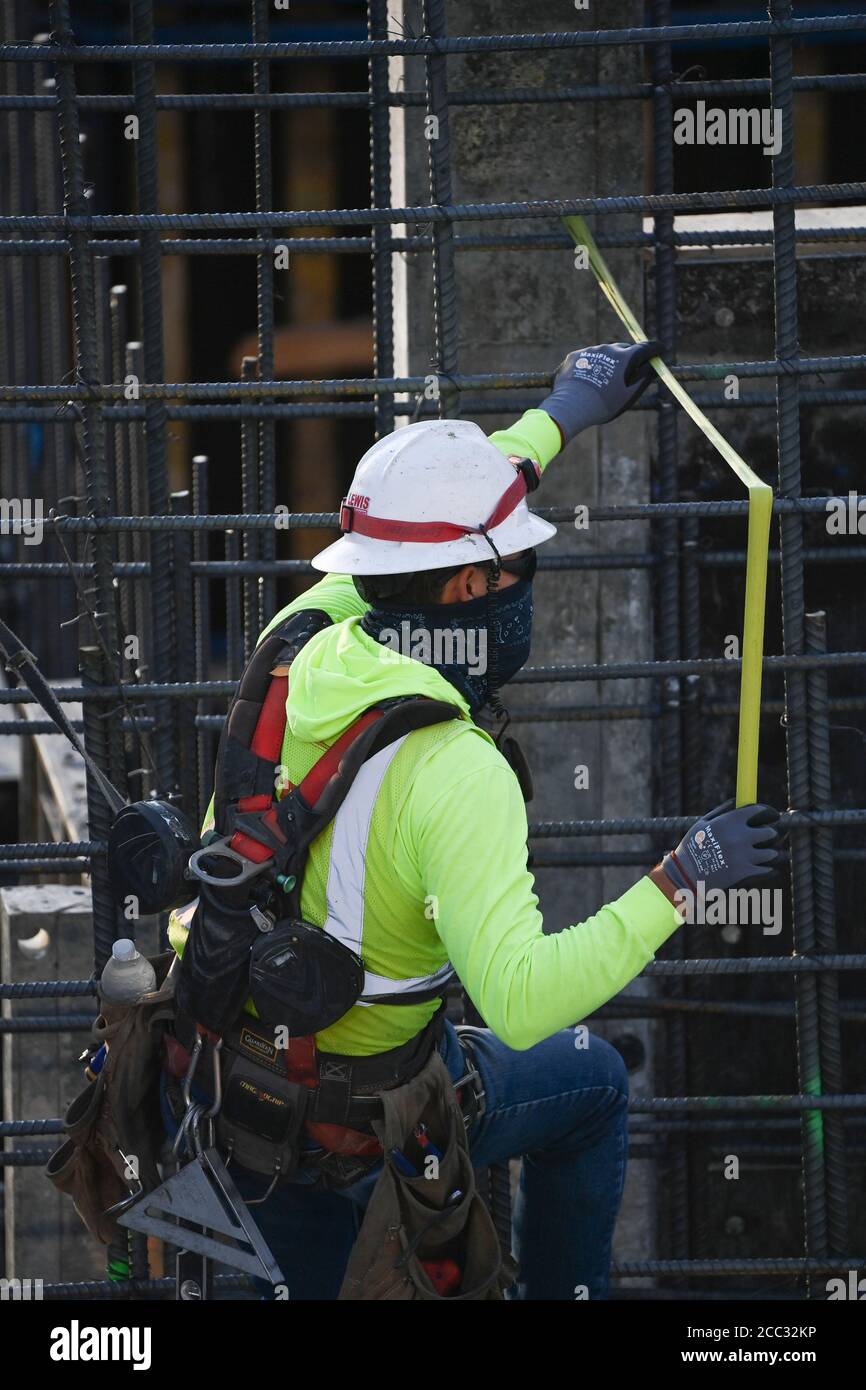 Construction worker wearing safety gear and face covering on job site ...