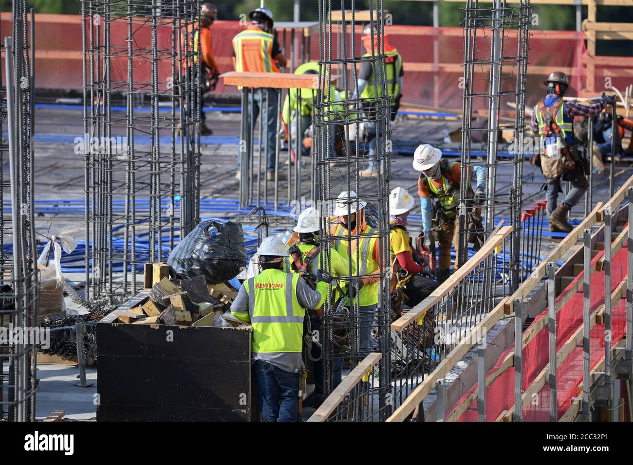 Construction crew wearing full safety gear and face coverings works on ...