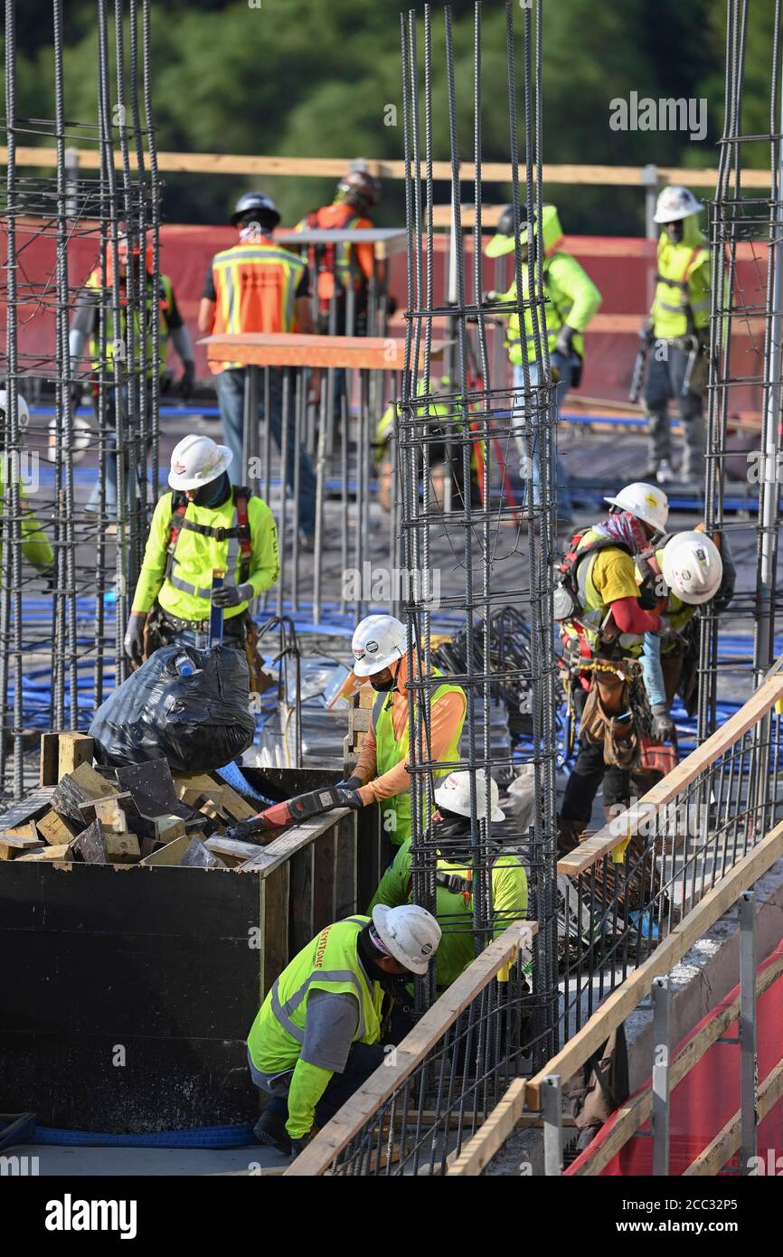 Construction crew wearing full safety gear and face coverings works on ...