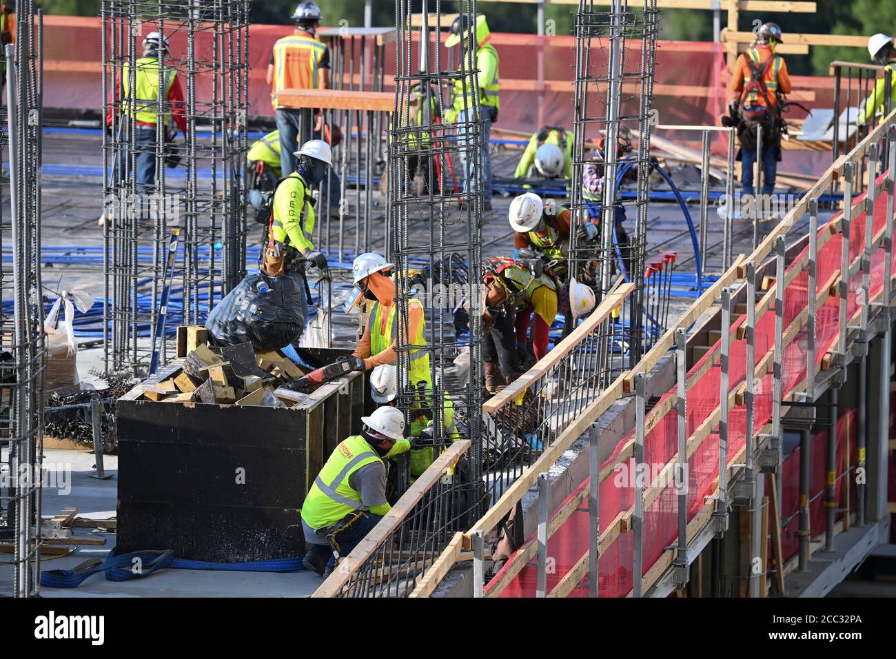 Construction crew wearing full safety gear and face coverings works on ...