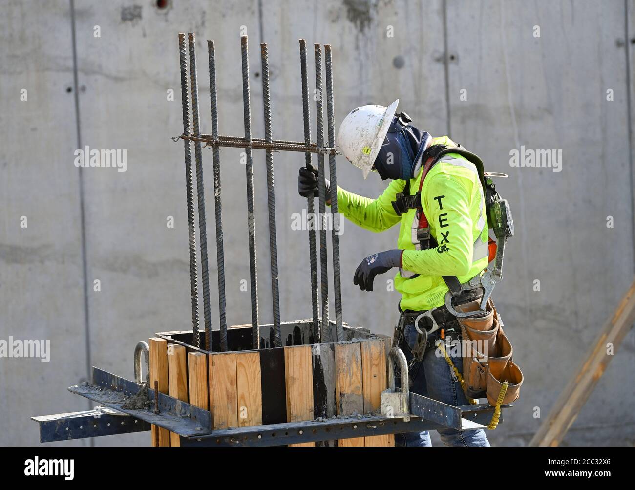 Construction worker wearing safety gear and face covering prepares ...