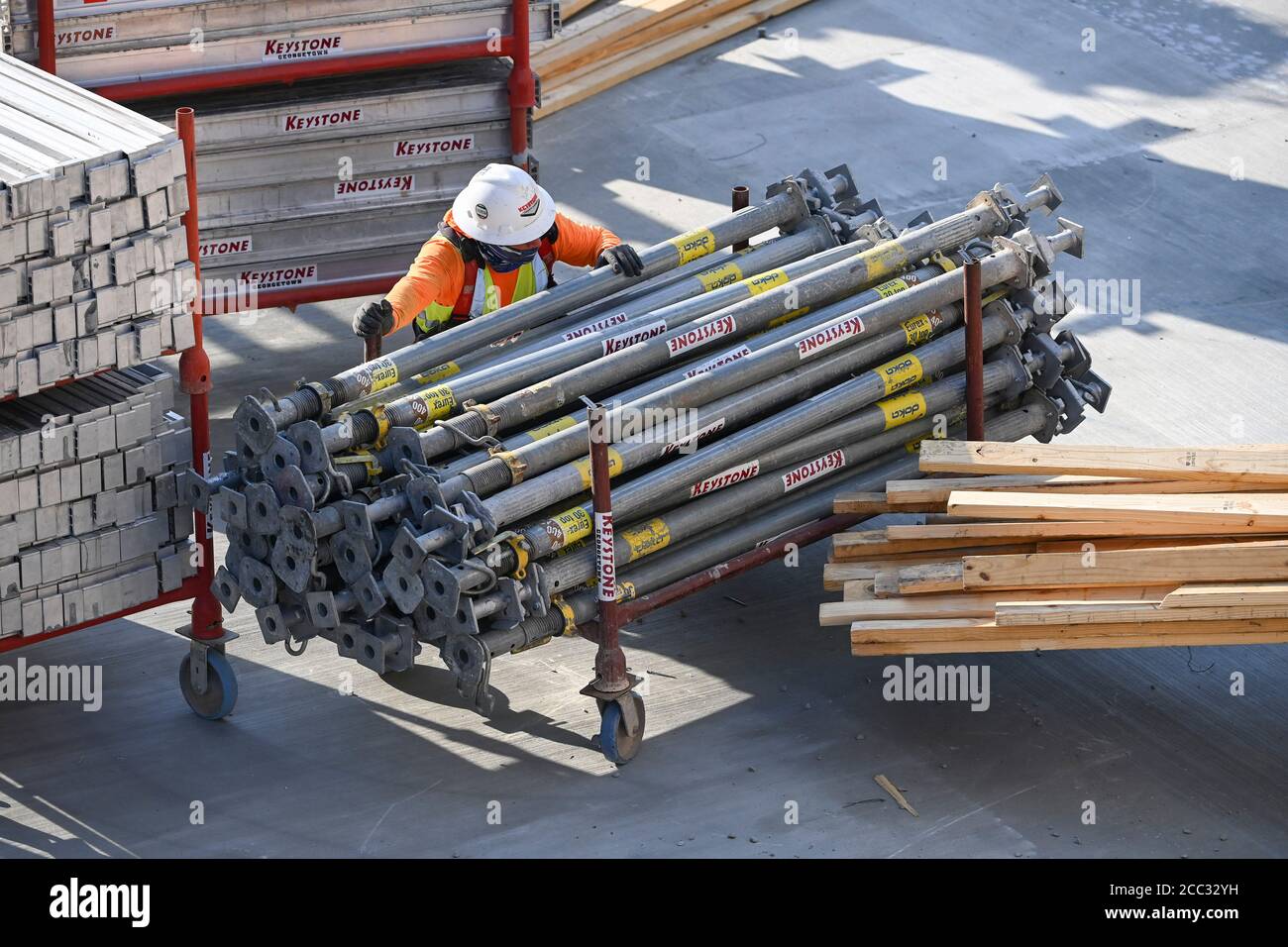 Construction worker wearing safety gear and face covering moves heavy ...