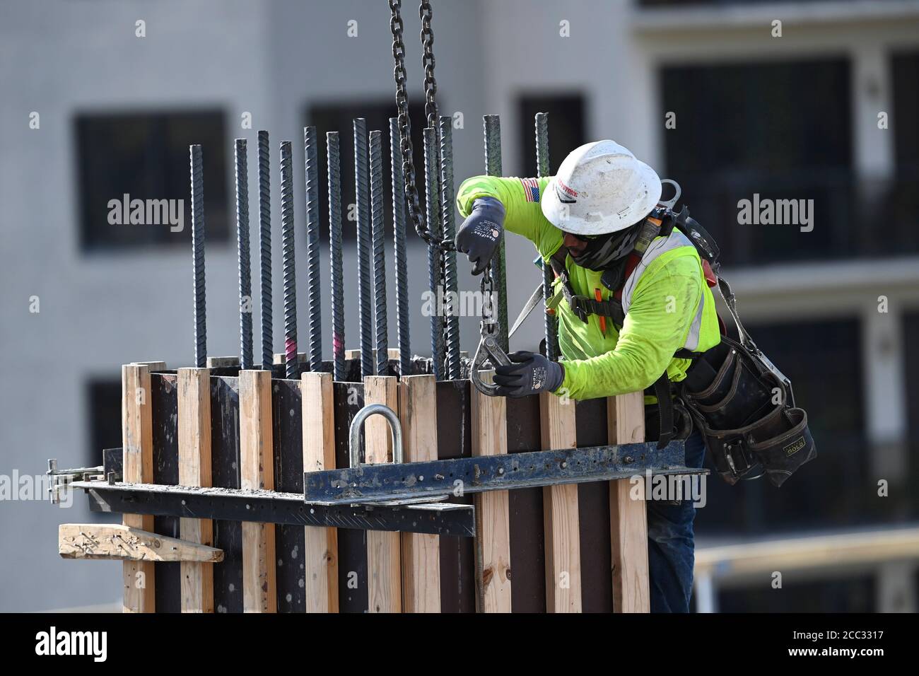 Construction worker wearing safety gear and face covering prepares ...
