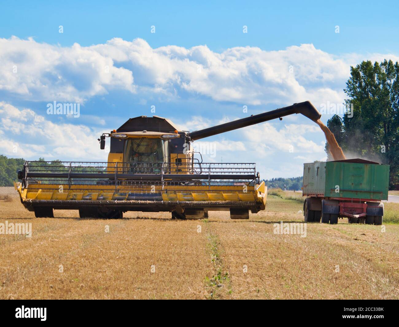 Combine harvester emptying grain tank on to a trailer during wheat ...