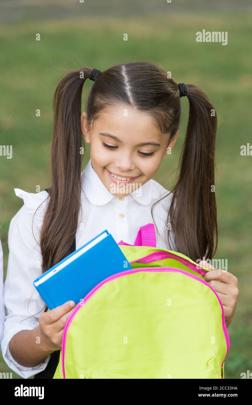 Schoolgirl putting book inside backpack, ready for lessons concept ...