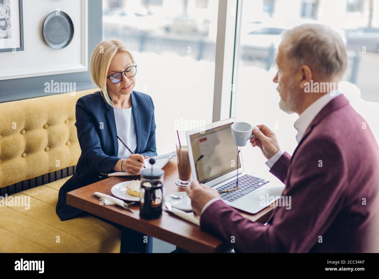 awesome woman in stylish clothes and old man having a business meeting ...