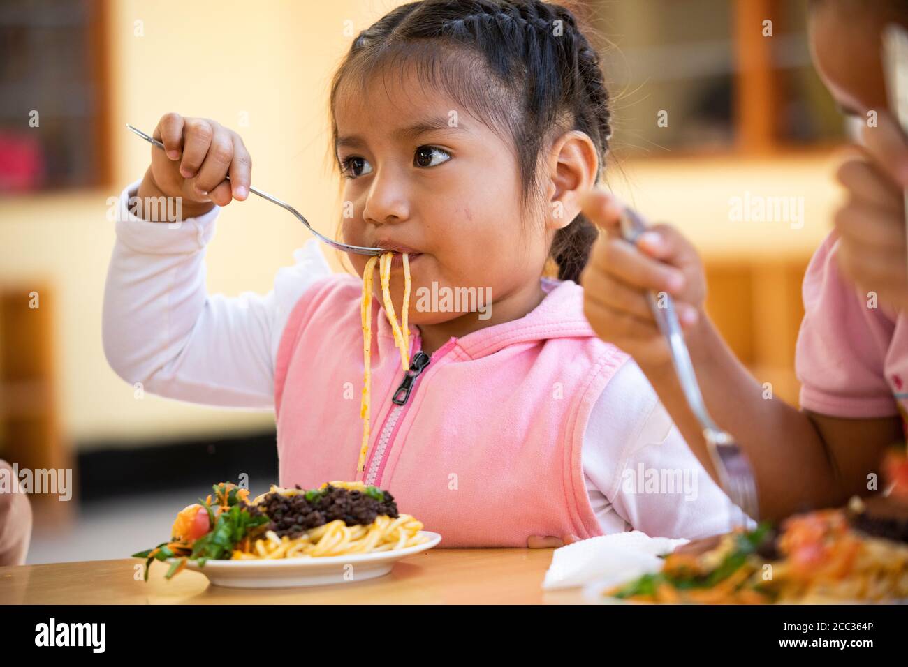 Children eat a nutritious lunch of pasta, vegetables and blood pudding ...