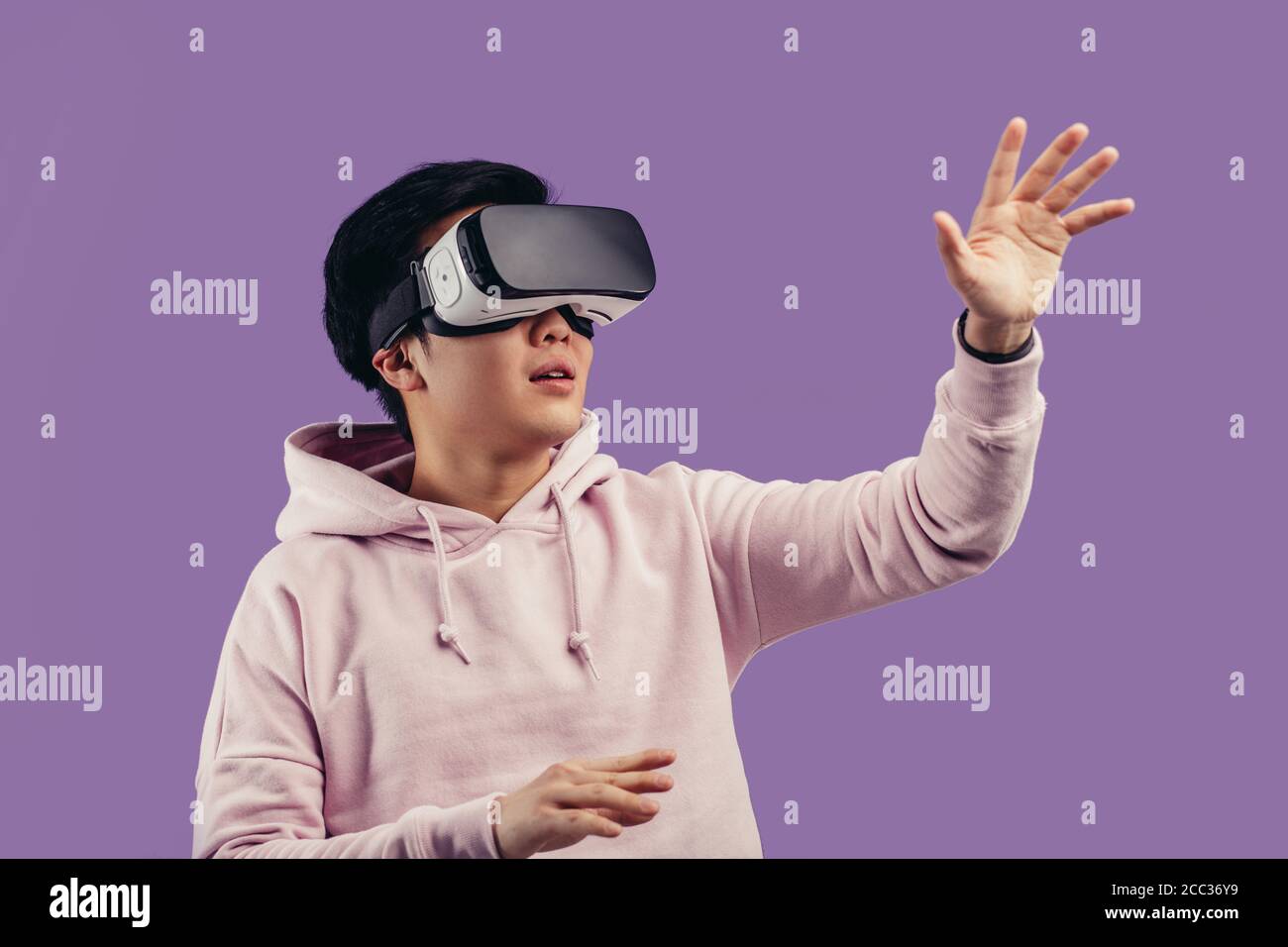 Amazed positive chinese male gamer wearing virtual reality goggles ...