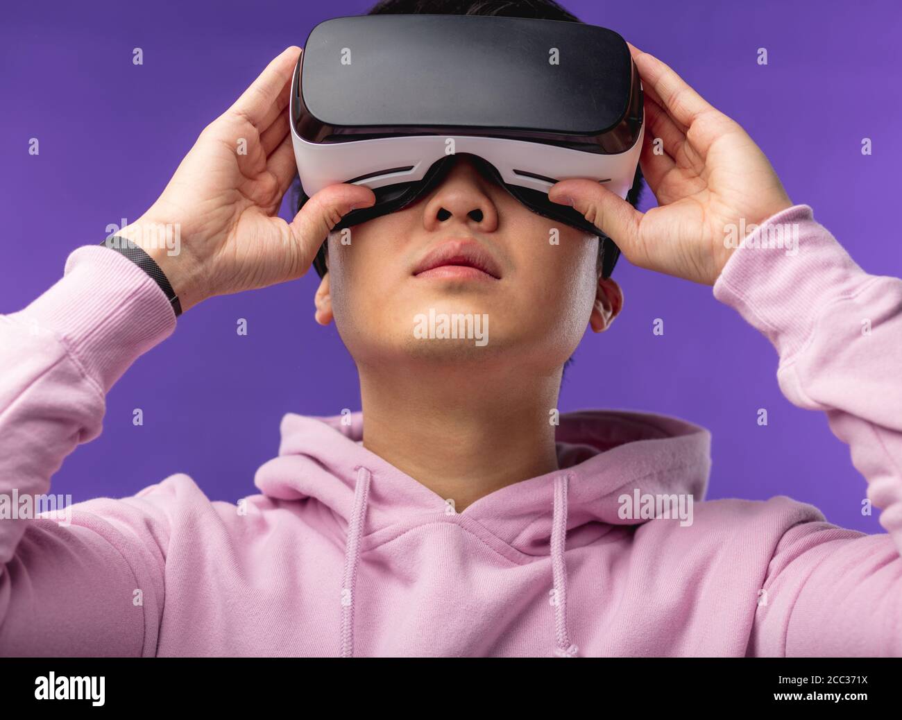 Amazed positive chinese male gamer wearing virtual reality goggles ...