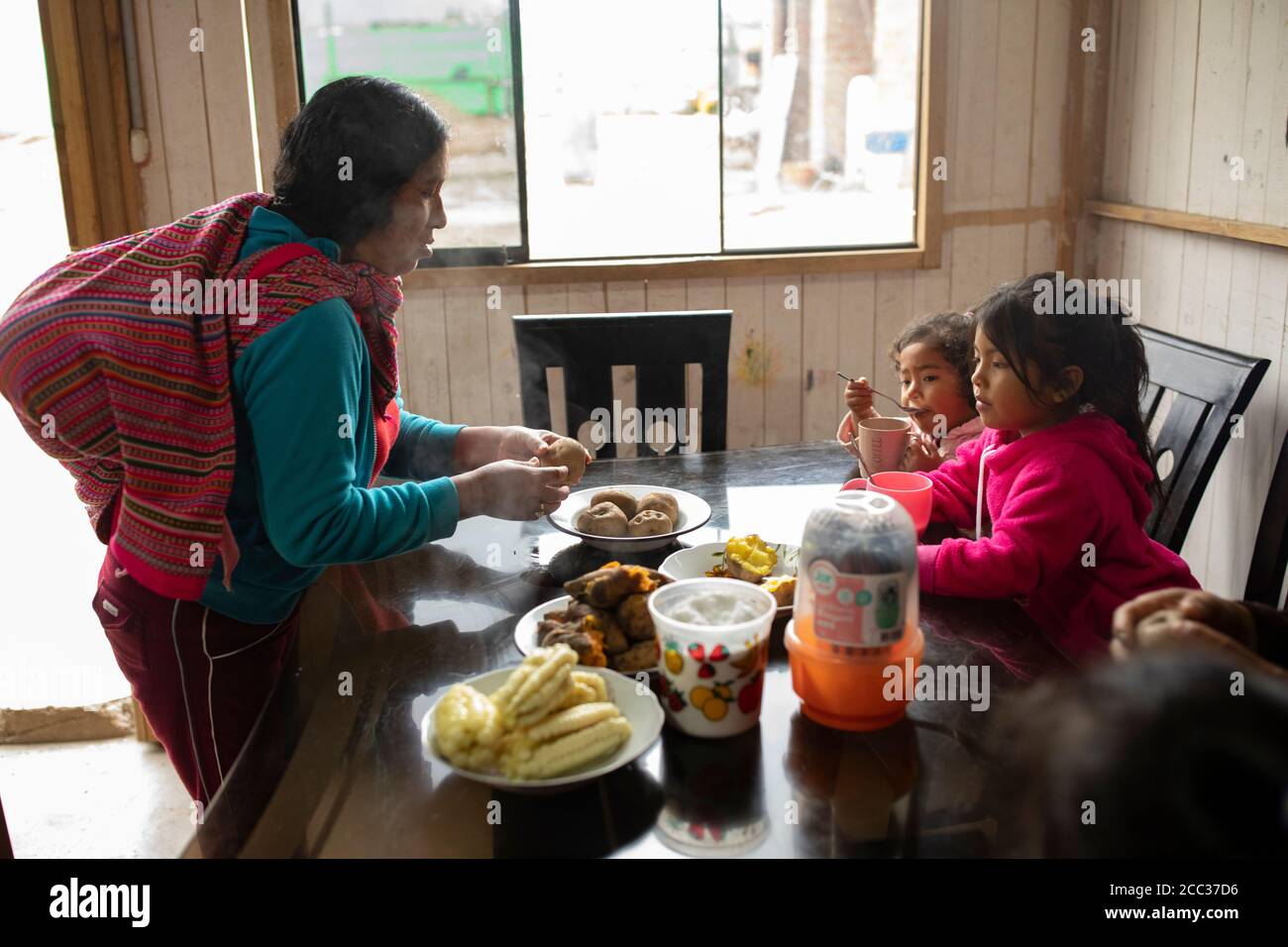 A mother serves her children a breakfast of corn and sweet potatoes at ...