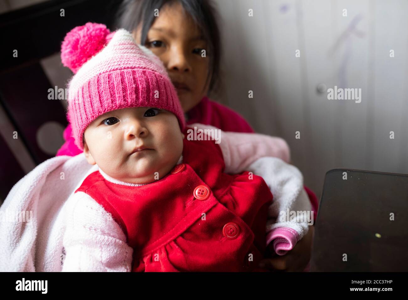 A newborn baby is held by her young sister at their home in Pachamac ...
