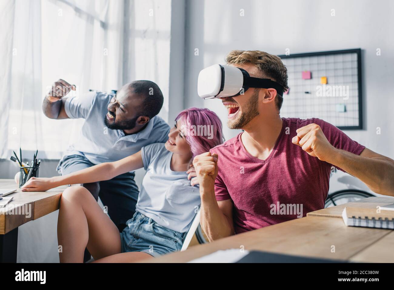 Selective focus of multicultural business people showing yes gesture while using vr headset in ...