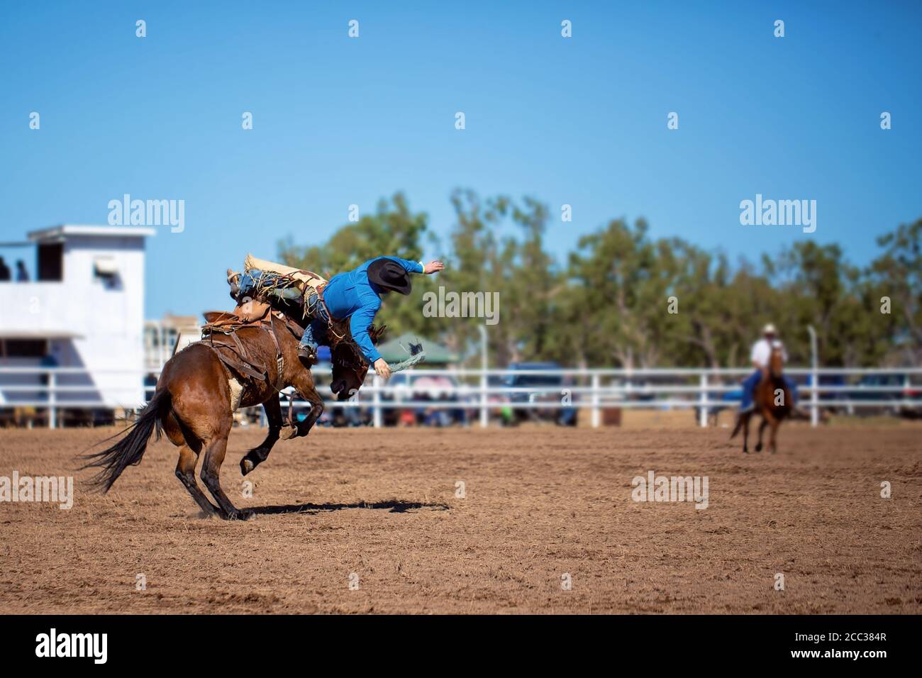 A cowboy riding a bucking bronco horse at an Australian country rodeo ...