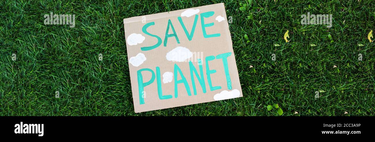 Horizontal crop of placard with save planet lettering on green grass ...