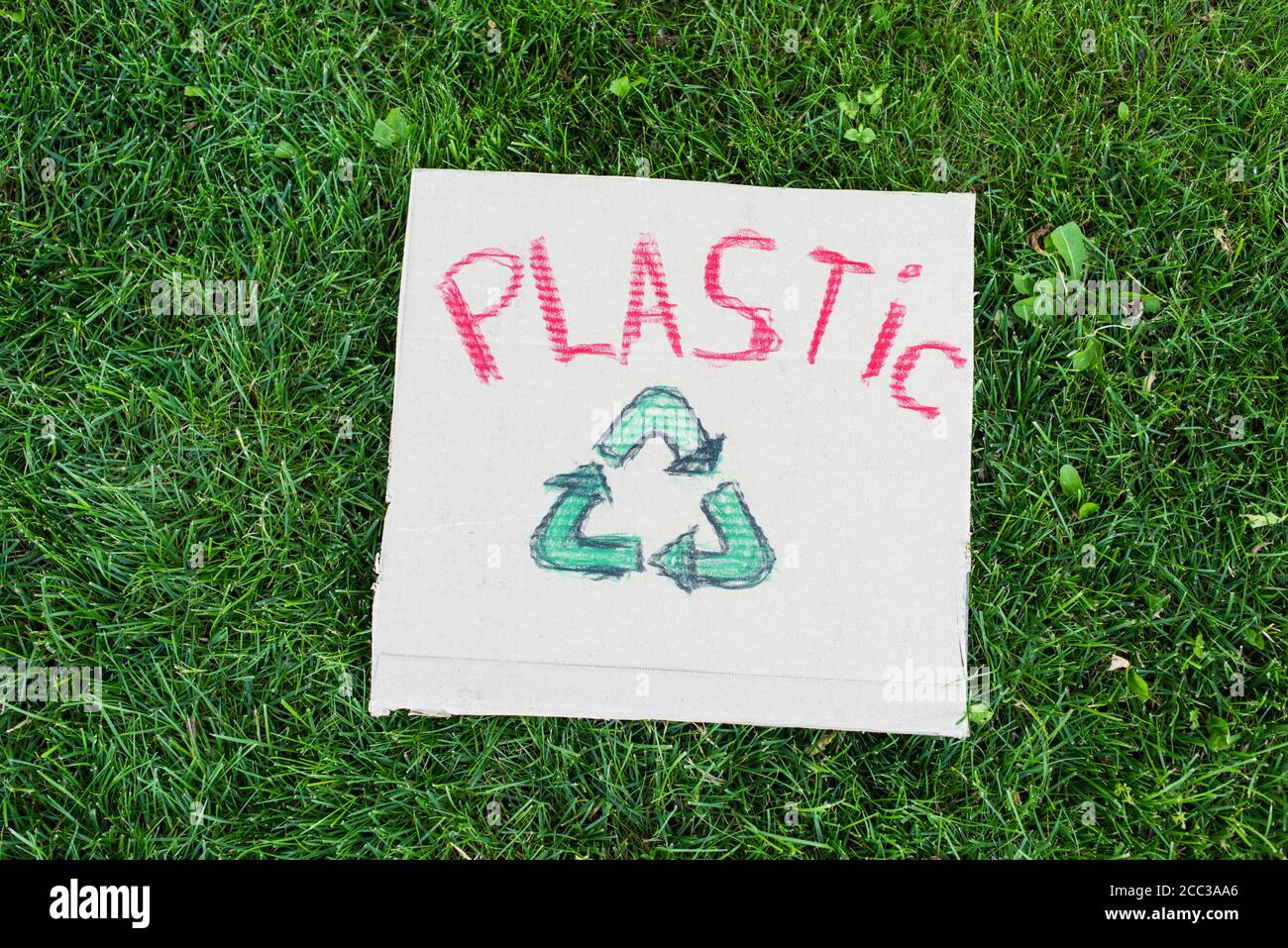 Top view of recycle sign and plastic lettering on placard on green ...