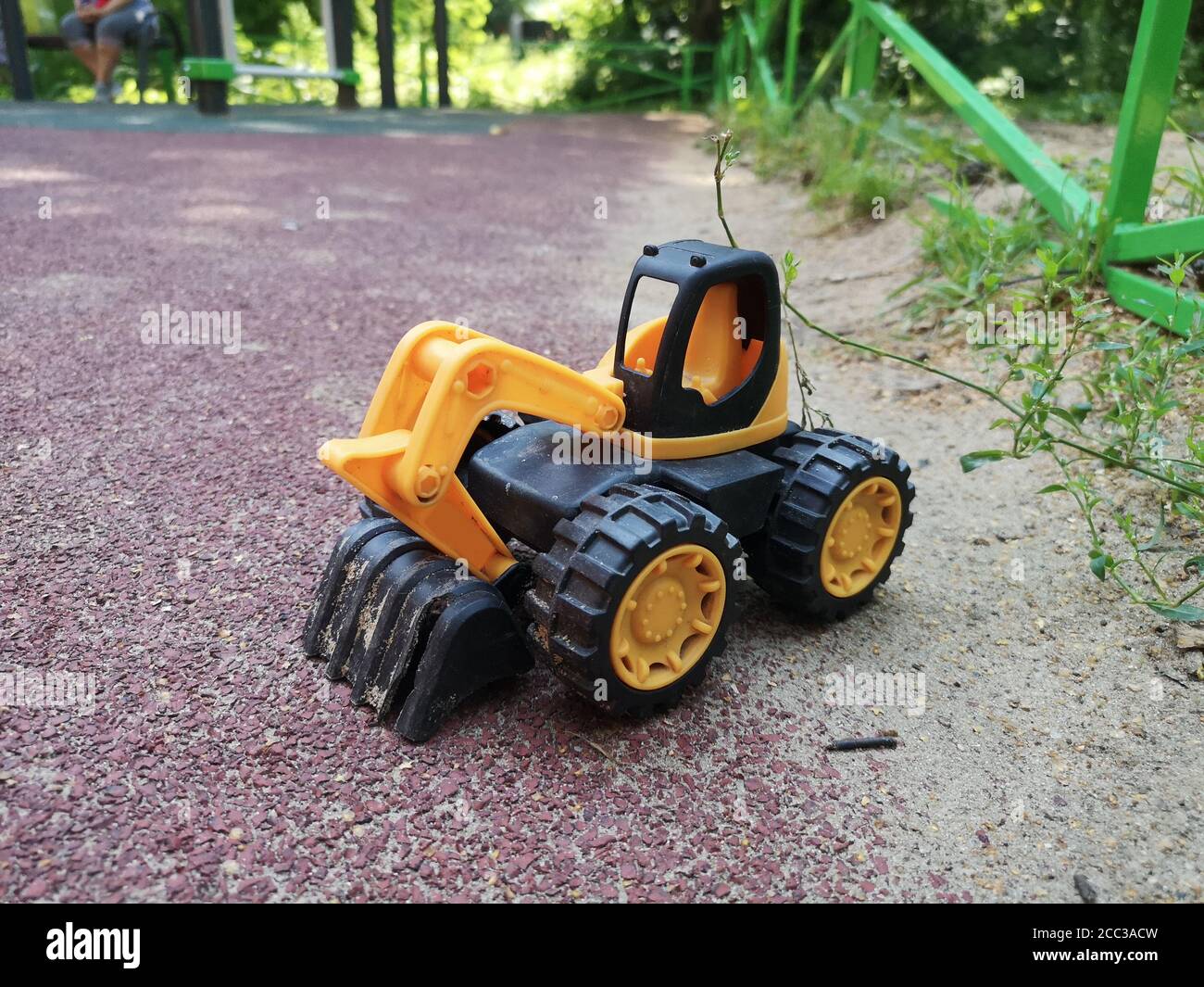 Small toy yellow excavator on rubber playground Stock Photo - Alamy