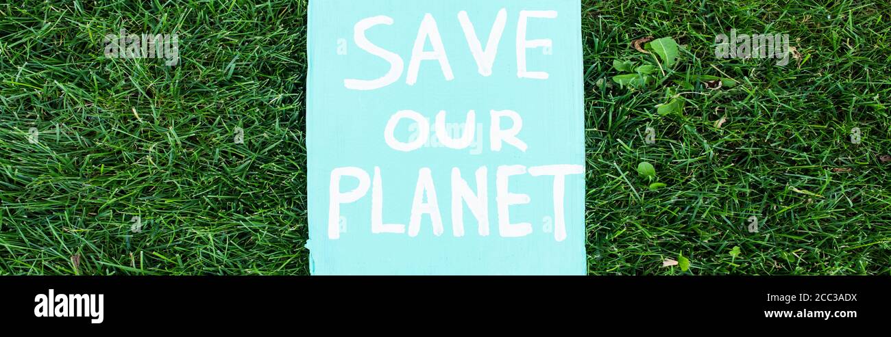 Horizontal concept of placard with save our planet lettering on grass ...