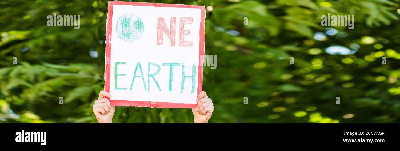 Horizontal concept of man holding placard with one earth lettering with ...