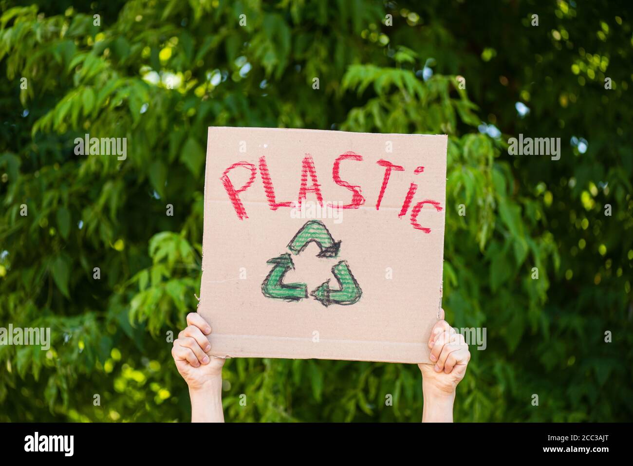 Partial view of man holding placard with plastic recycle sign with ...