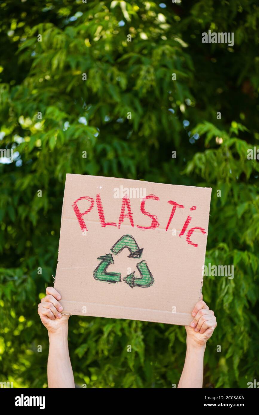 Cropped view of man holding placard with plastic lettering and recycle ...