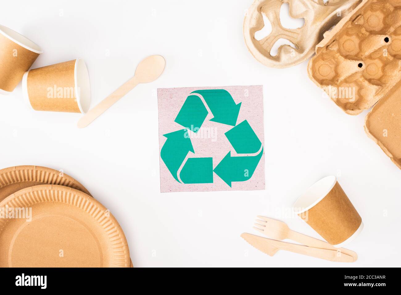 Top view of card with recycle sign near disposable tableware on white ...