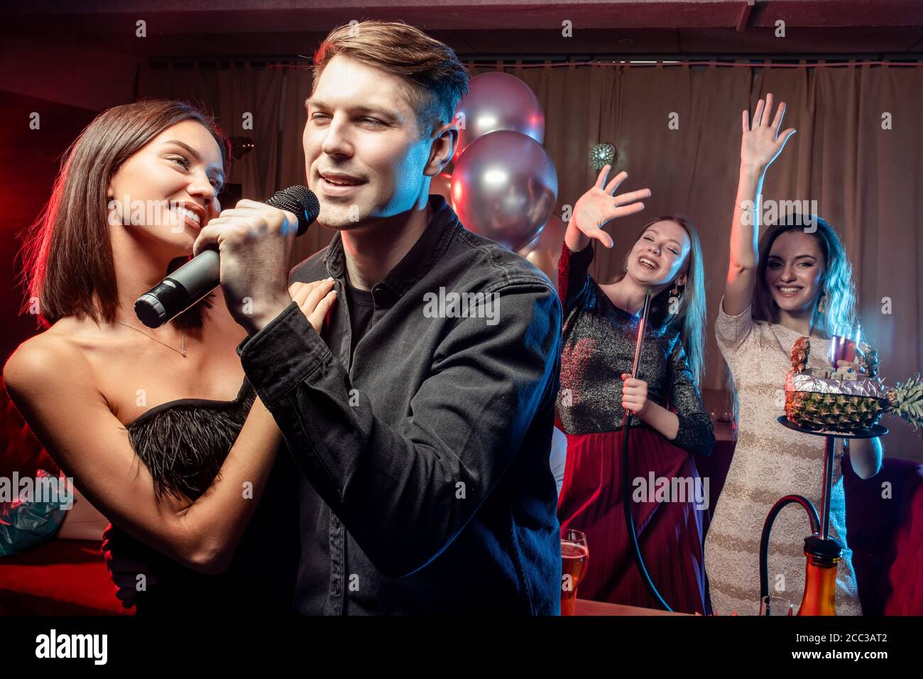 lovely young caucasian couple spend free time, celebrating in karaoke ...