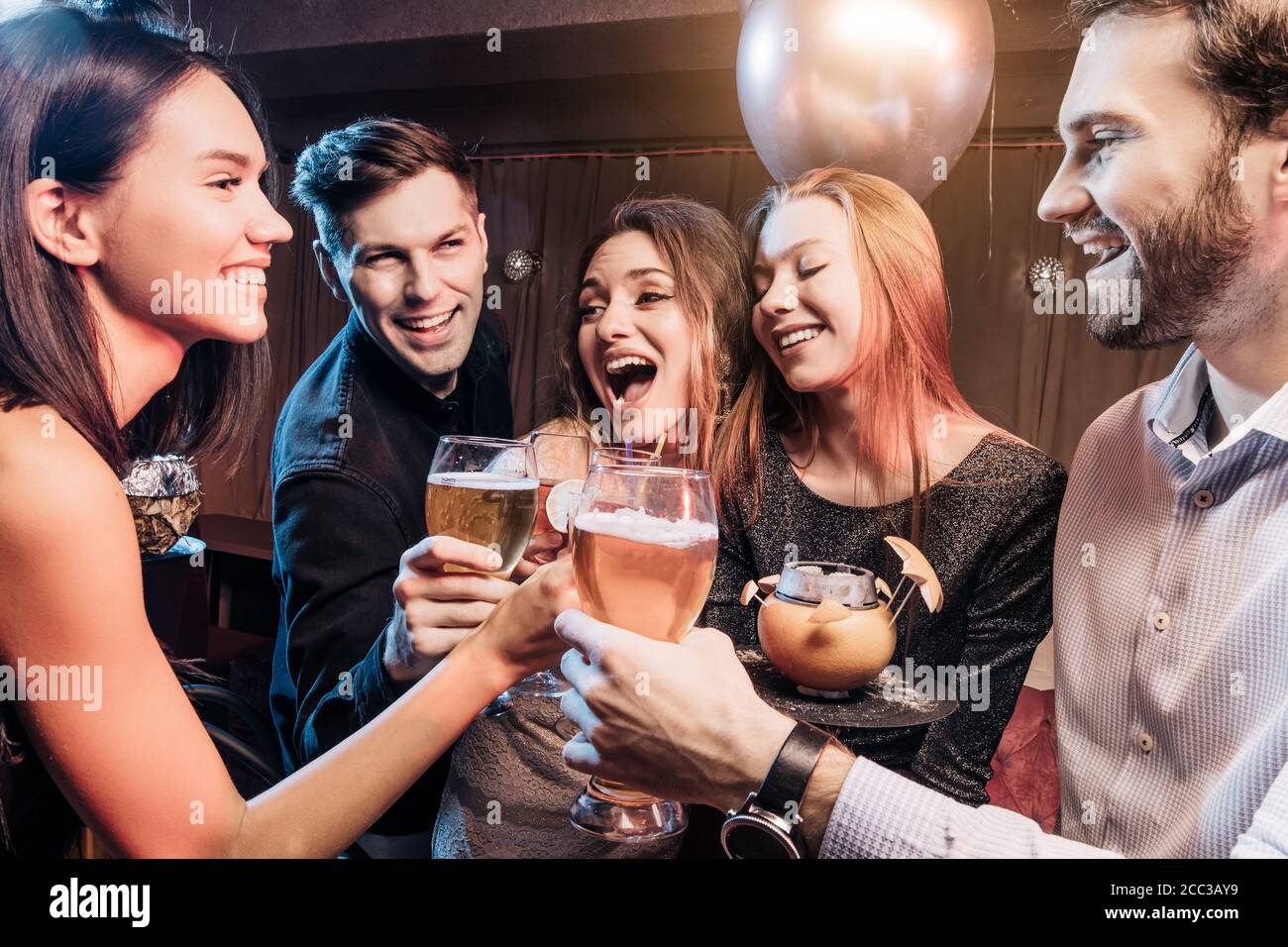cheerful group of people smile and drink and have fun togeher in ...