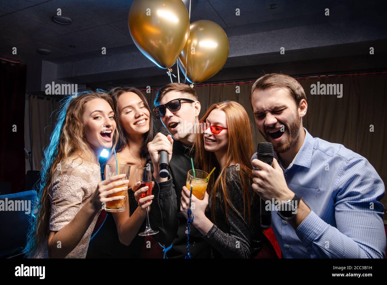young caucasian people celebrating birthday in karaoke bar, chill out ...
