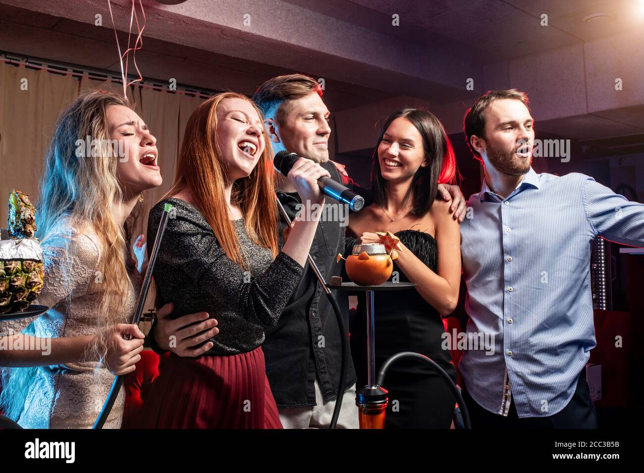 young ladies and guys chilling and rocking in karaoke bar, spend day ...
