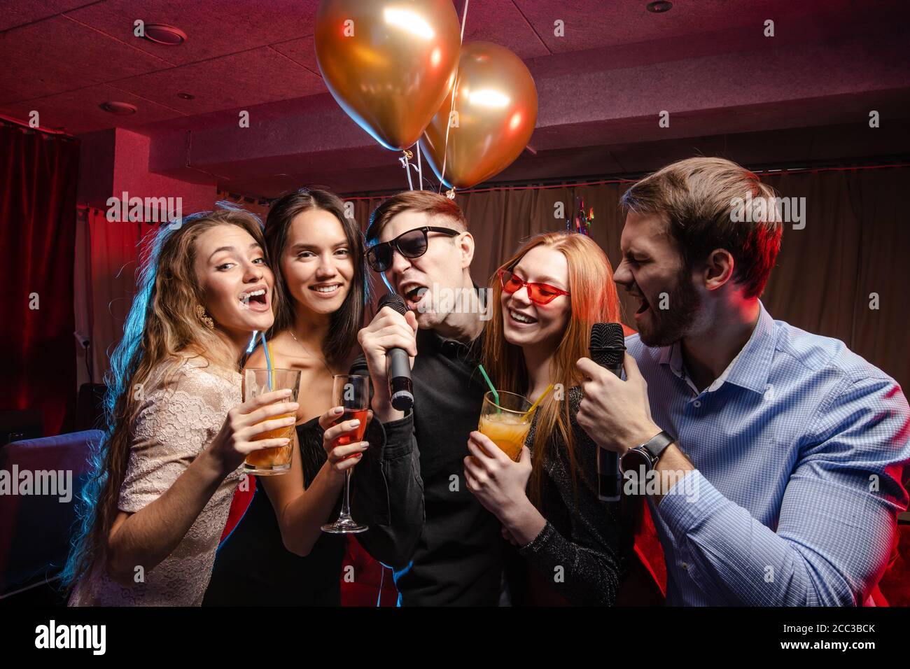 young and happy caucasian friends spend party time in karaoke bar, sing ...