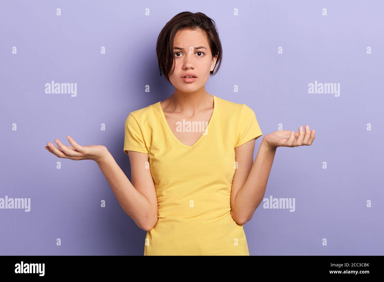 serious, frustrated young girl with raised arms shrugging shoulders ...