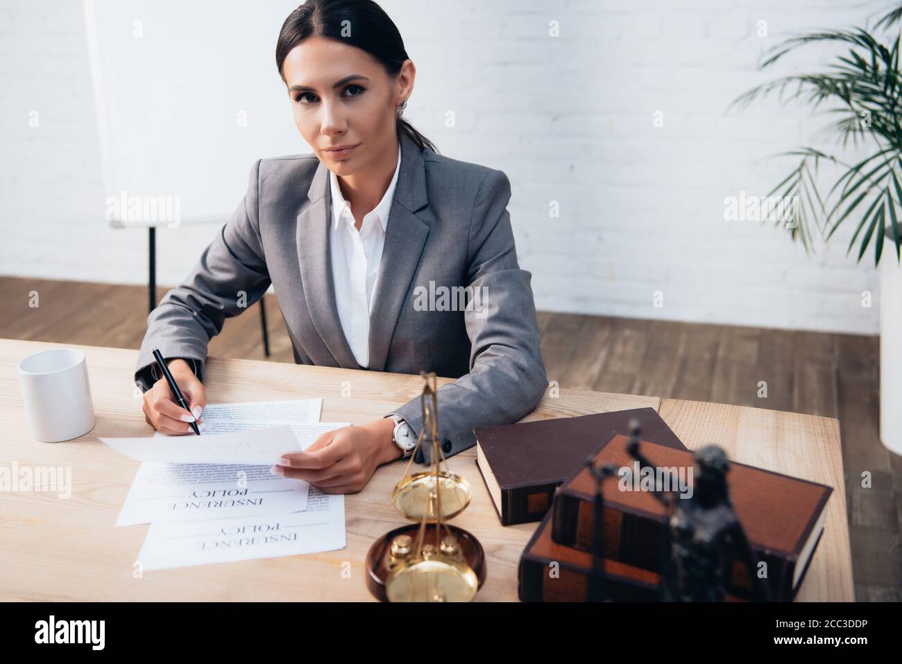 selective focus of brunette lawyer in formal wear holding pen near ...
