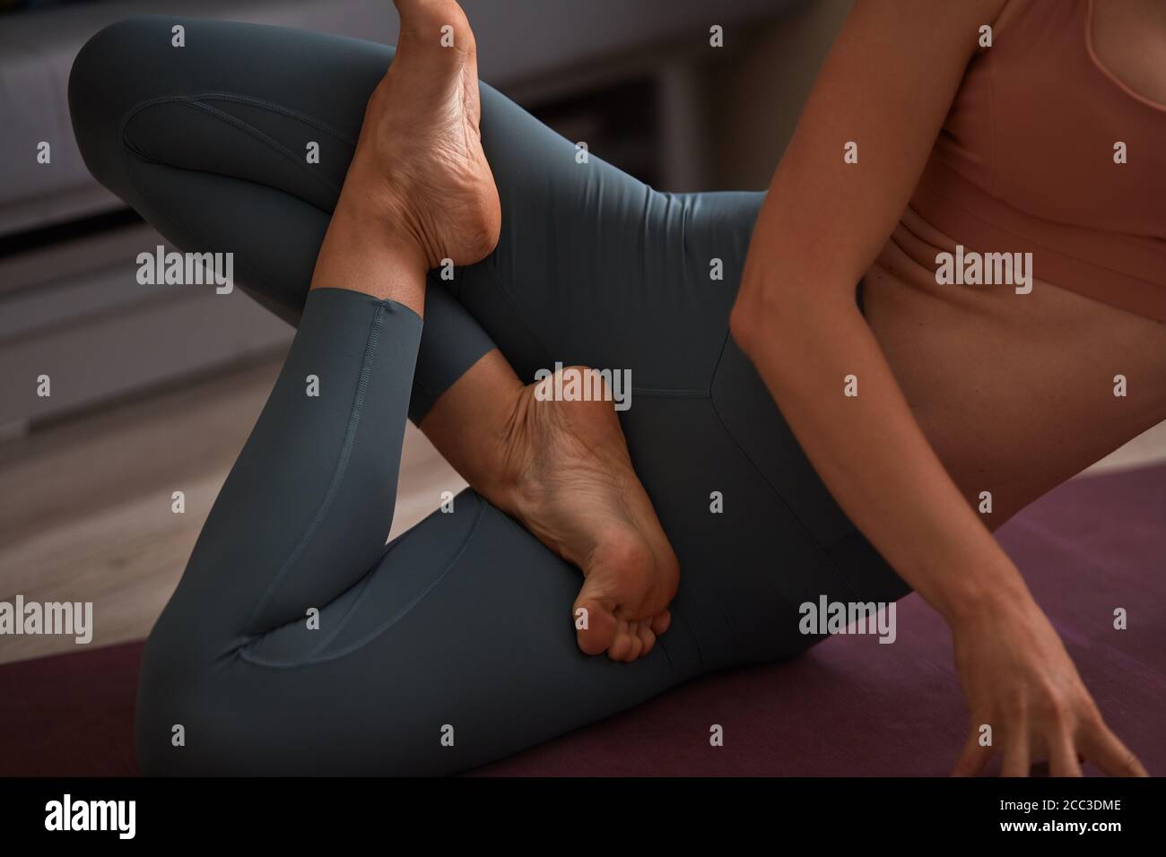 Close-up of young woman in grey leggins practice yoga in room. Female ...