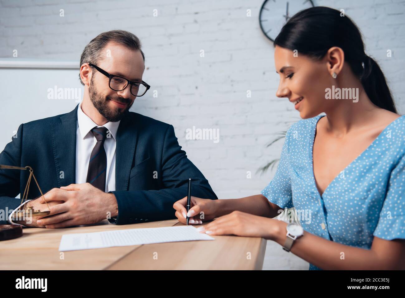 selective focus of bearded lawyer in glasses looking at woman signing ...