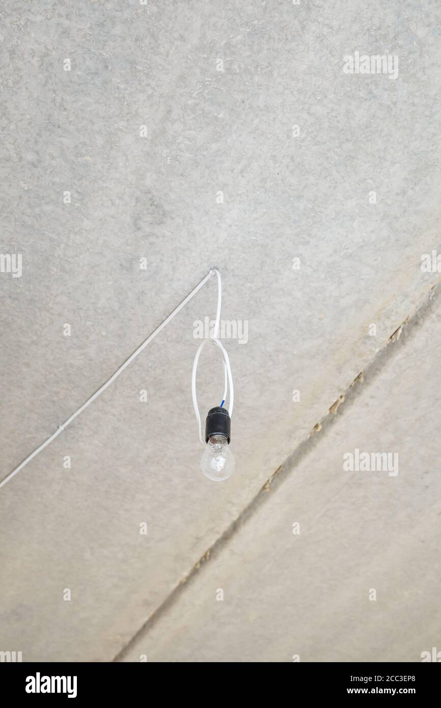 Light bulb on the ceiling. Lonely light bulb and wire sticking out of ...