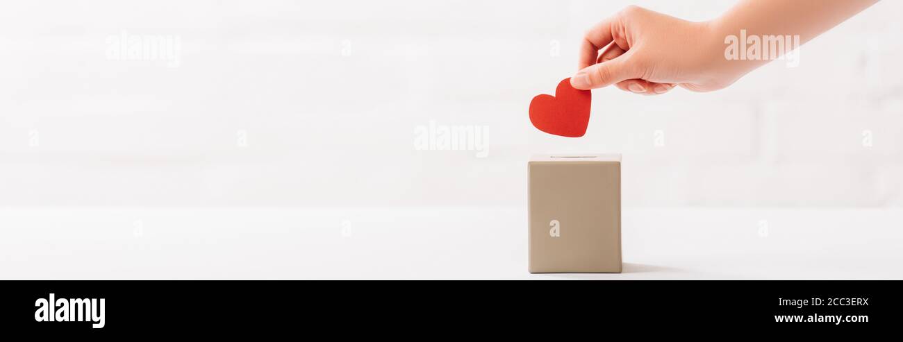 cropped view of female hand putting red heart in box on white ...